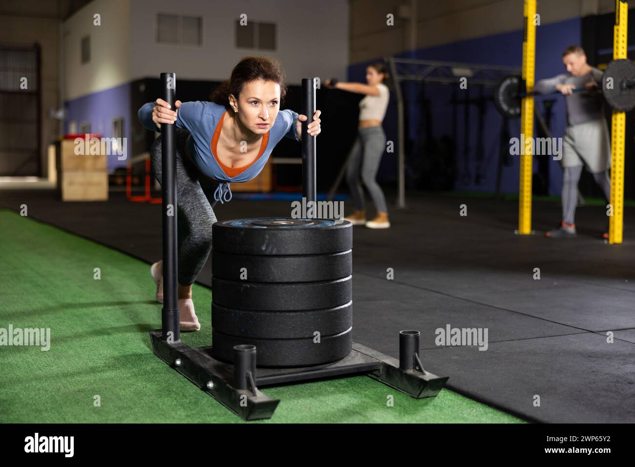 Fitness young girl pushing sled at gym, cross exercise with equipment ...