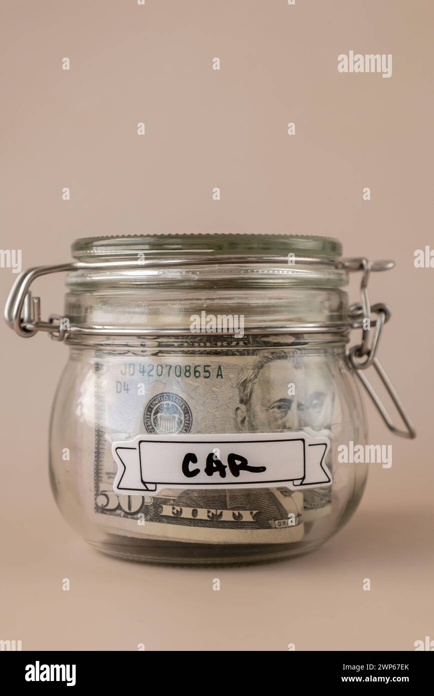 Glass jar full of American currency dollars cash banknote with text CAR ...