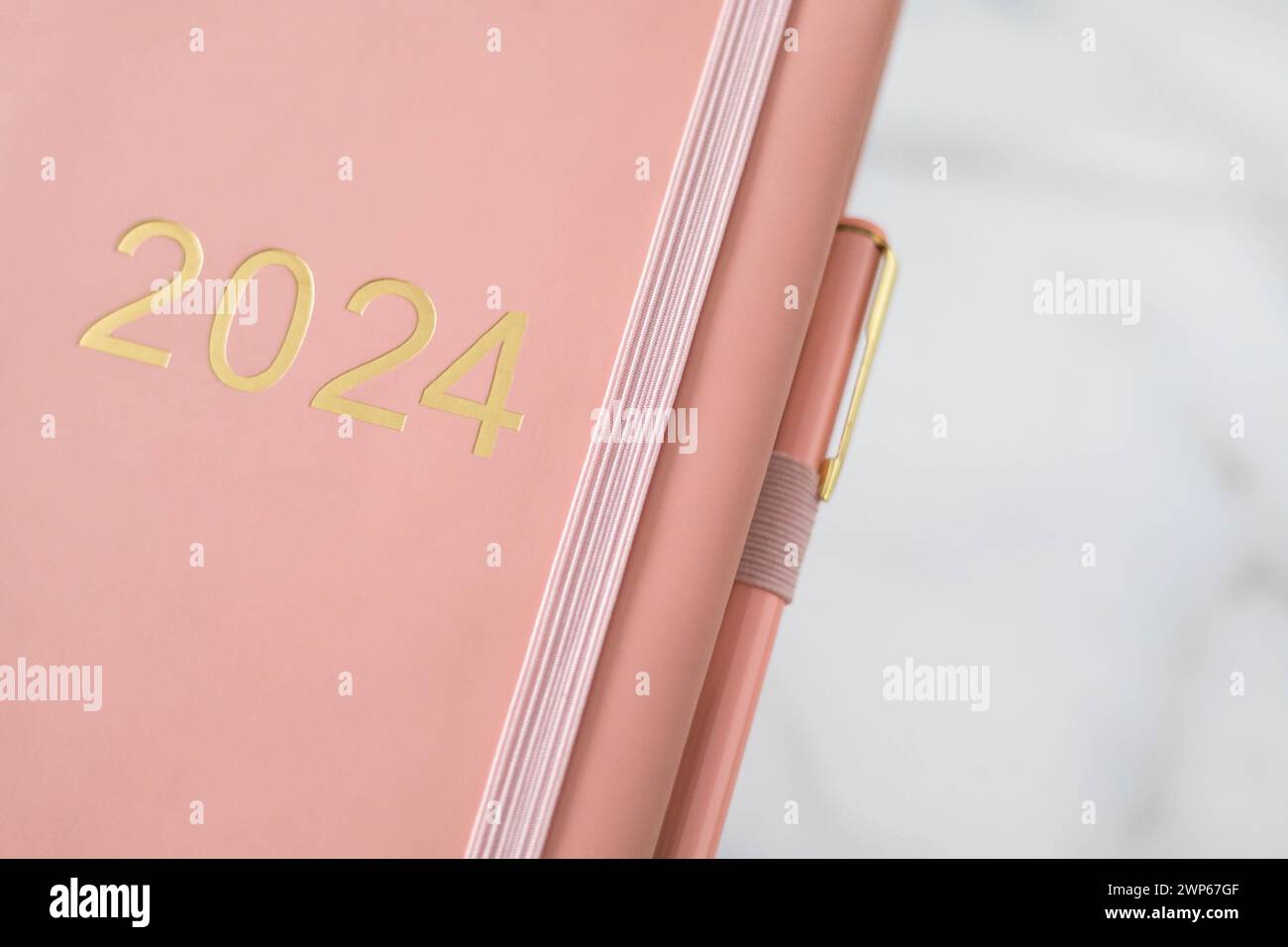 Pink coral colored diary for the year 2024, pen, marble background ...