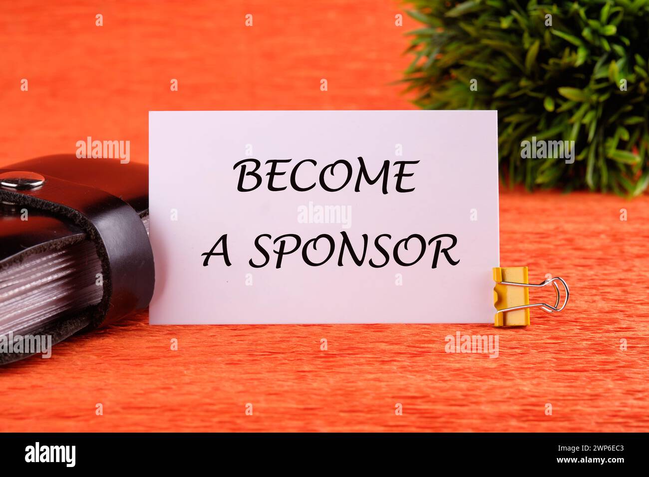 BECOME A SPONSOR text written on a white card near the business card ...
