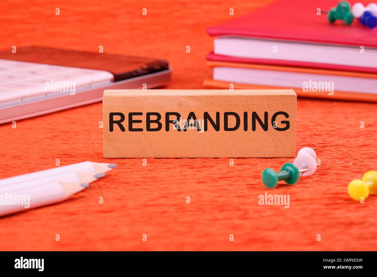 rebranding word written on a wooden block on an orange background next ...