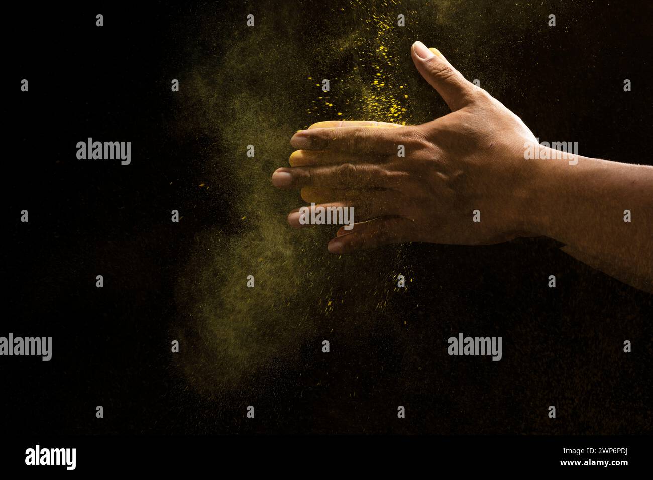 Close up view of hand creating a vibrant cloud of dust of holi powder ...