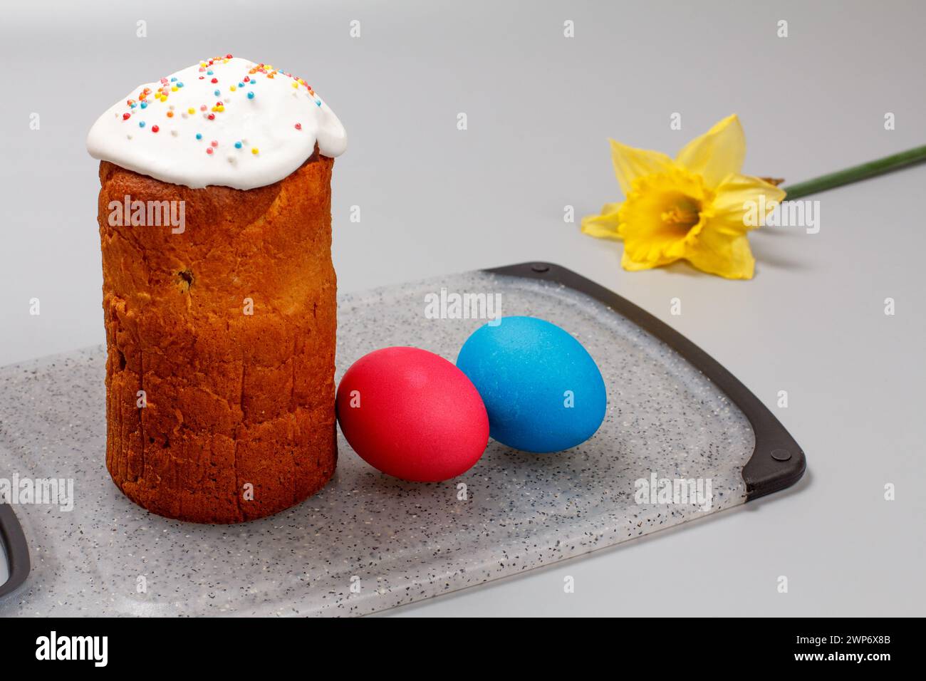 Easter cake and colorful Easter eggs on the cutting board with a bud of ...
