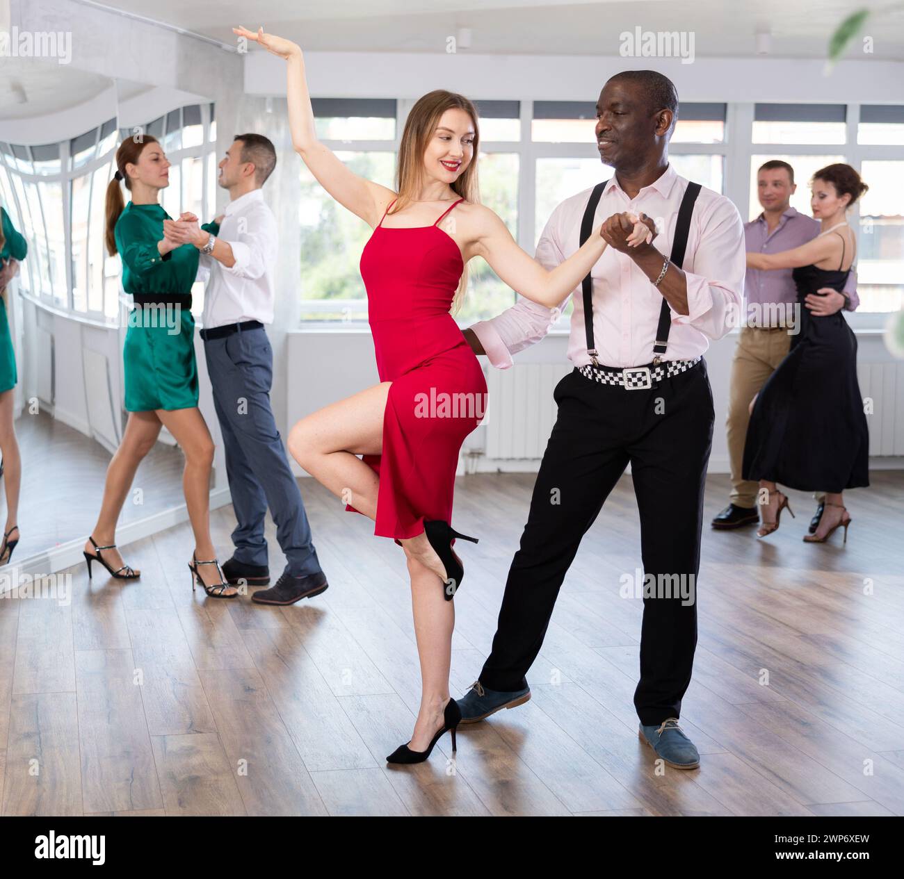 Woman with African man dancing waltz in couple during lesson at studio ...