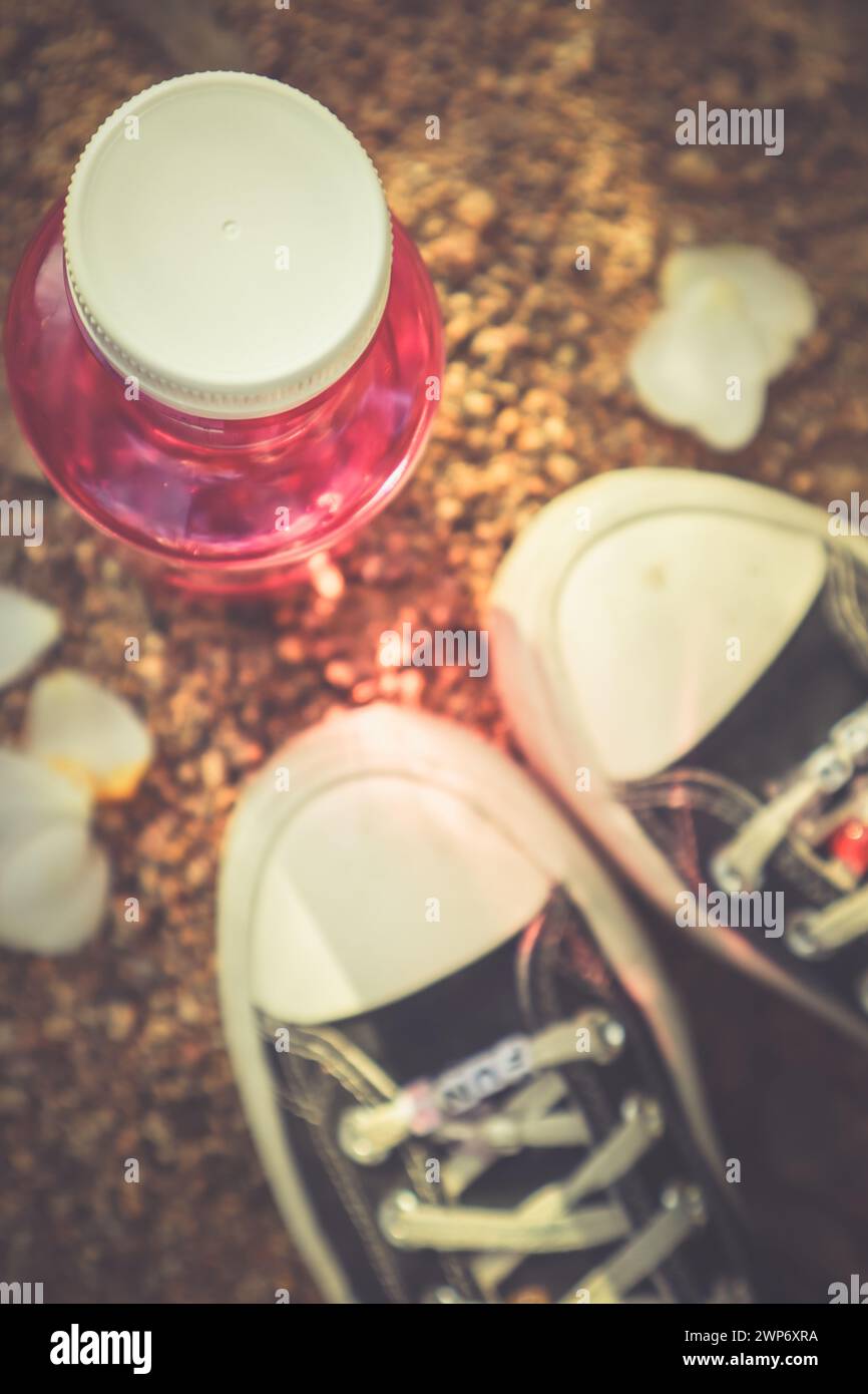 Pink plastic bottle with water drink. Black white sneakers Converse on ...