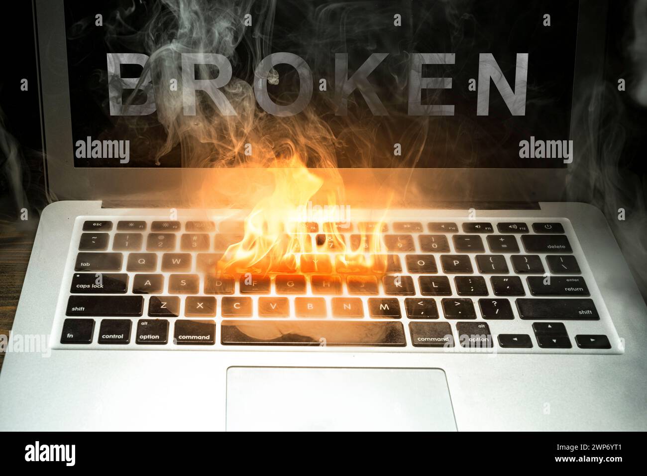 Close up laptop burned with flame and smokes on a wooden desk with ...