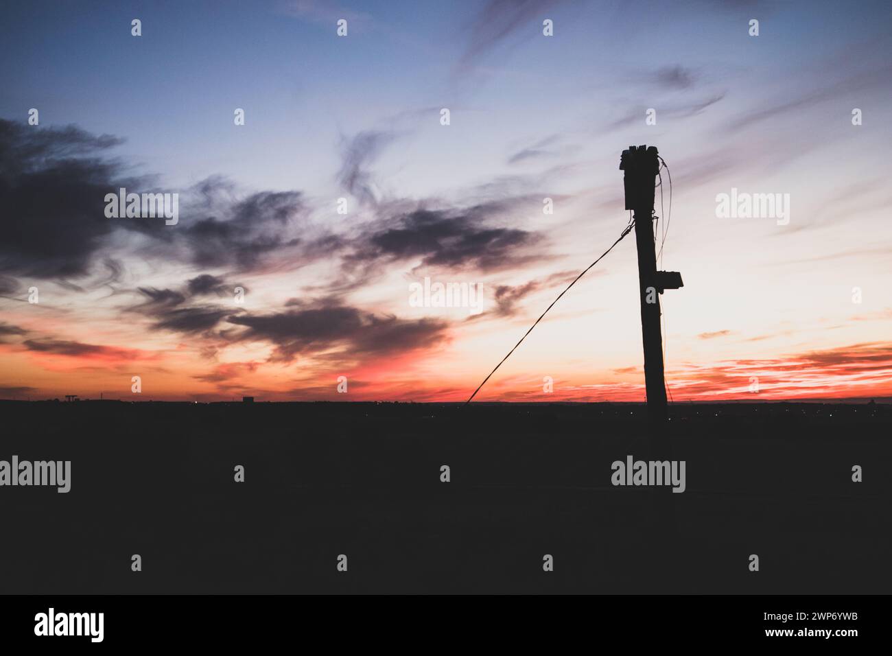 Power line pole silhouette against cloudy sunset sky. Electric wire ...