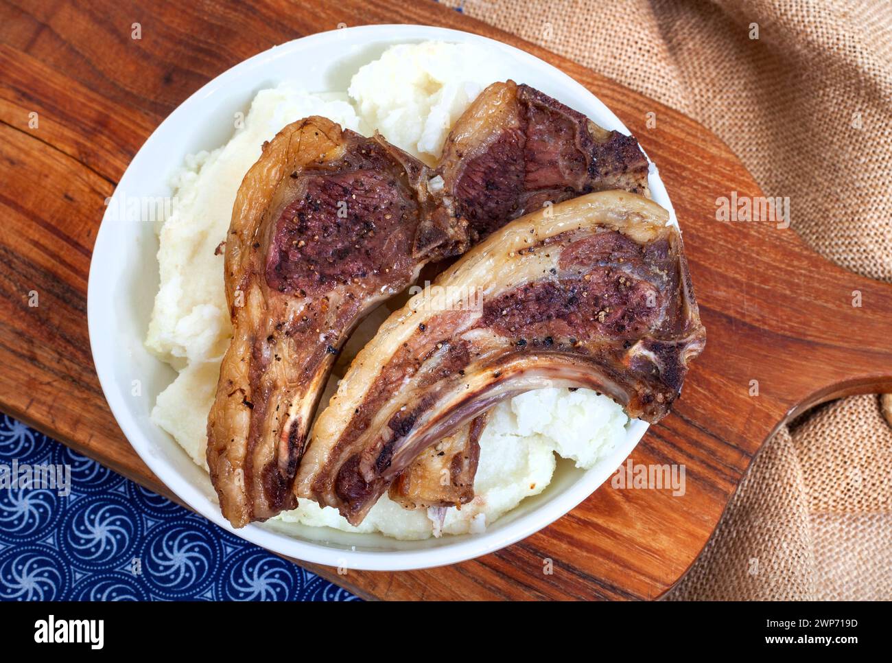 three lamb rib chops with pap or maize meal on rustic chopping board ...