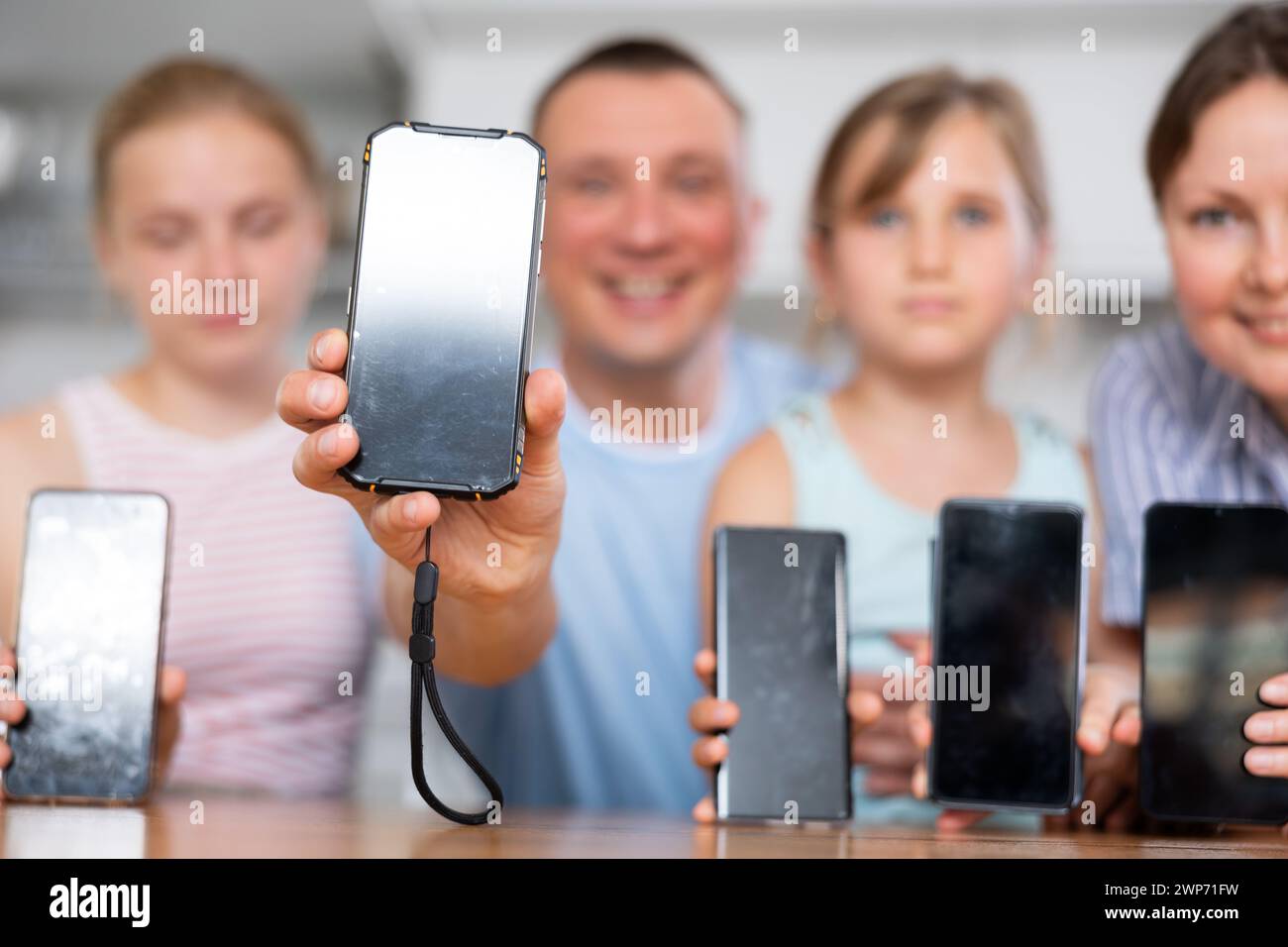 Happy family of four showing screens of their phones Stock Photo - Alamy