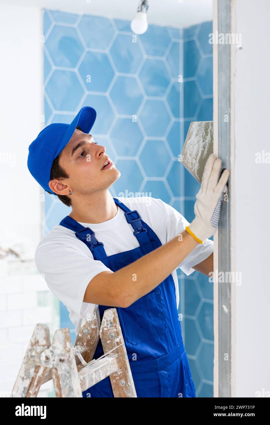 Professional male builder sticking ceramic tiles on the wall in ...