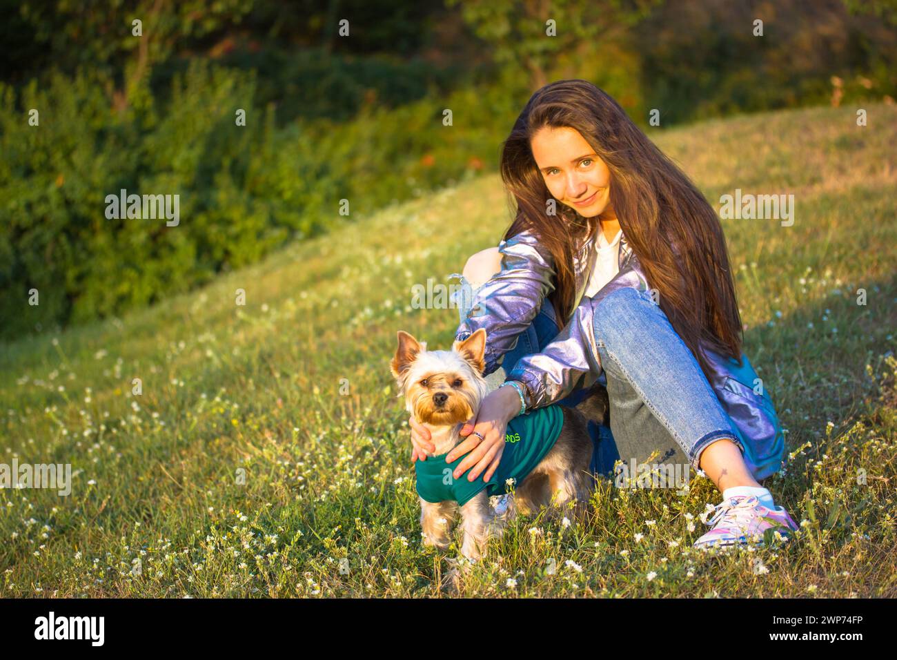 A young beautiful long-haired stylish girl in a silver raincoat, blue ...