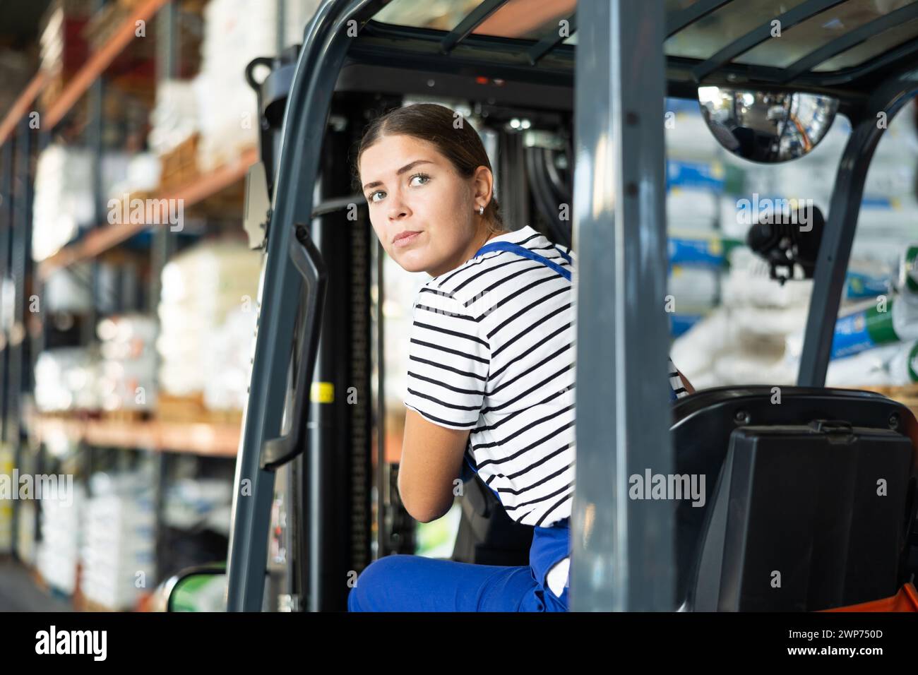 Girl works on fork lift loader in construction rack area warehouse ...