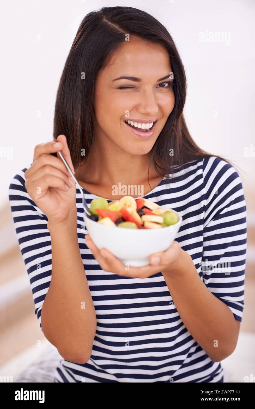 Fruit, portrait and wink with healthy eating woman, bowl and happy for ...