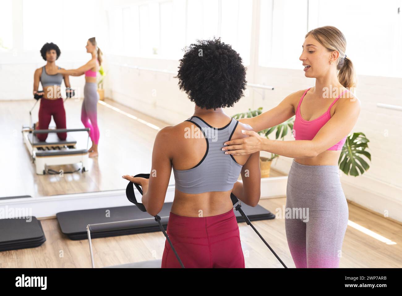 Fitness instructor assists a young biracial woman at the gym with ...