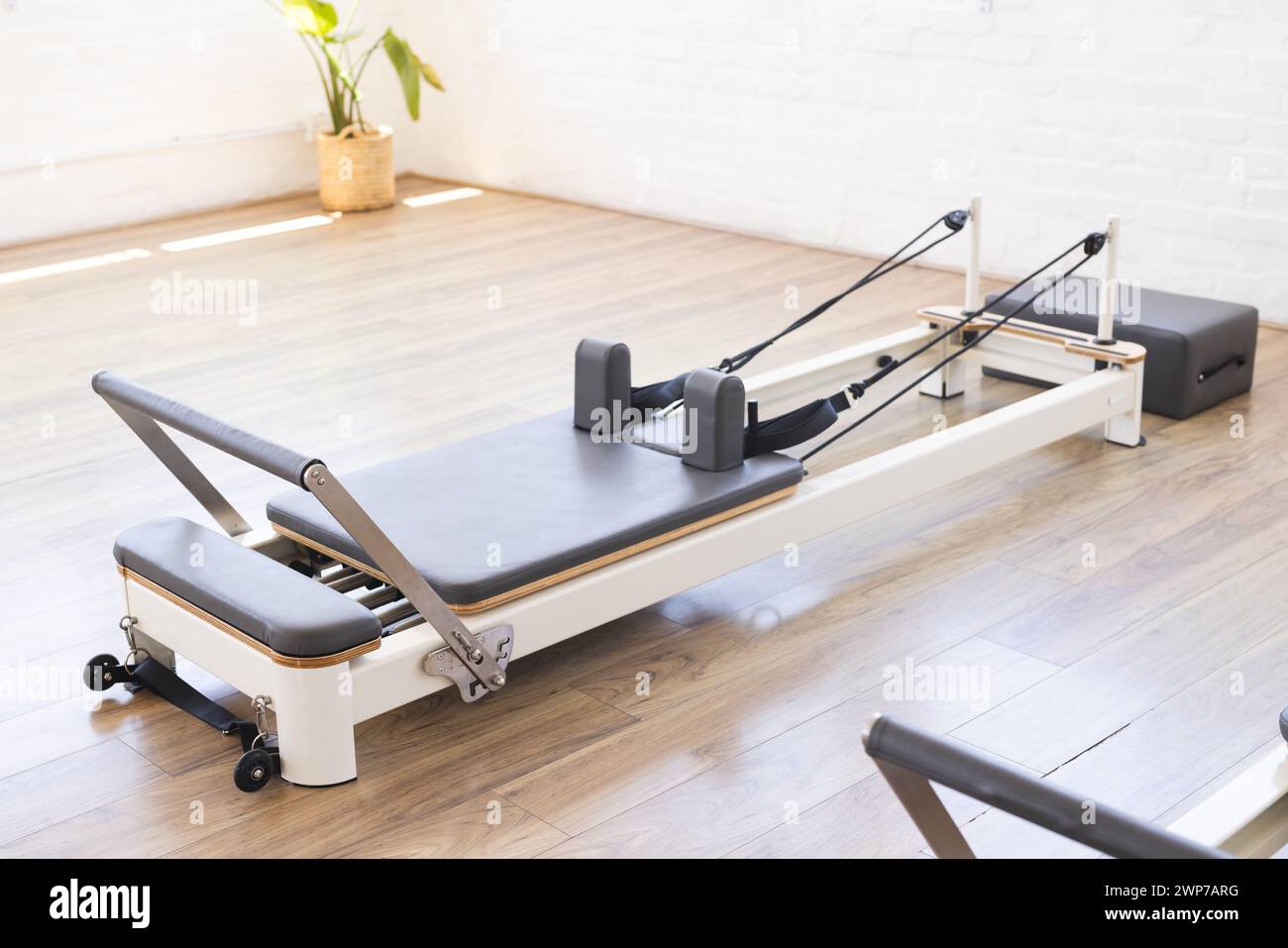 A Pilates reformer machine is ready for a workout in a bright studio ...