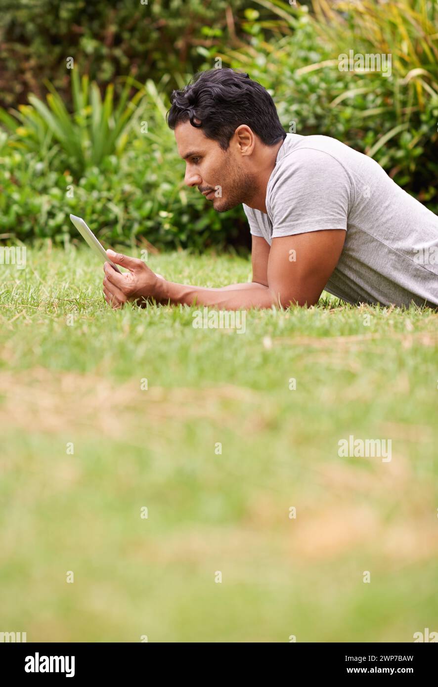 Man, outdoor and tablet on grass, browse and watching social media or ...