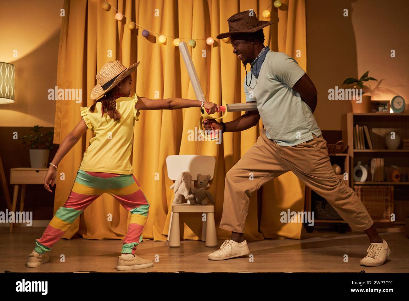 Portrait of smiling Black little girl in sword fight with father while ...