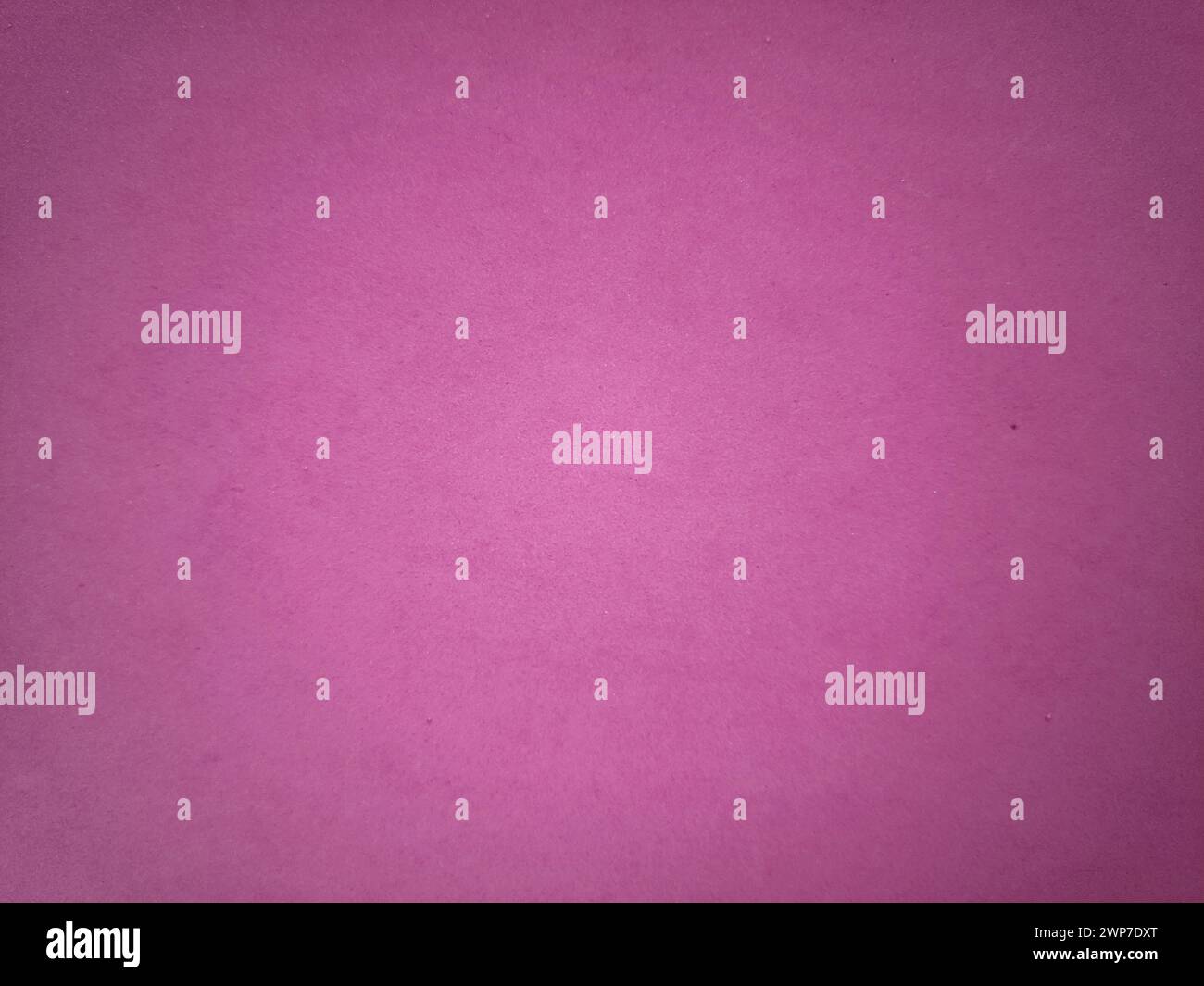 A sheet of dark pink paper with light vignetting around the edges ...