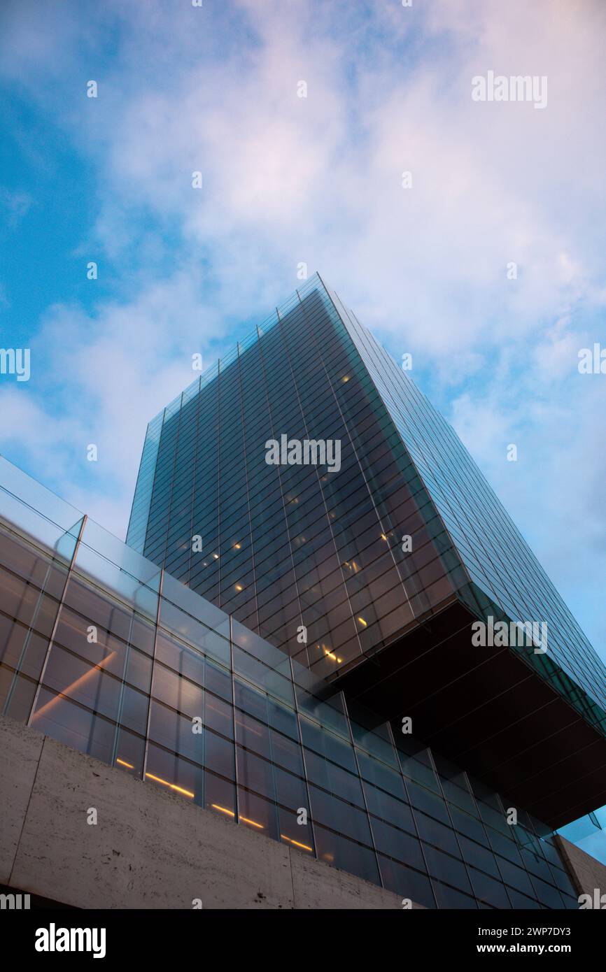 Blue glass facade of a tall business building with warm lighting inside ...