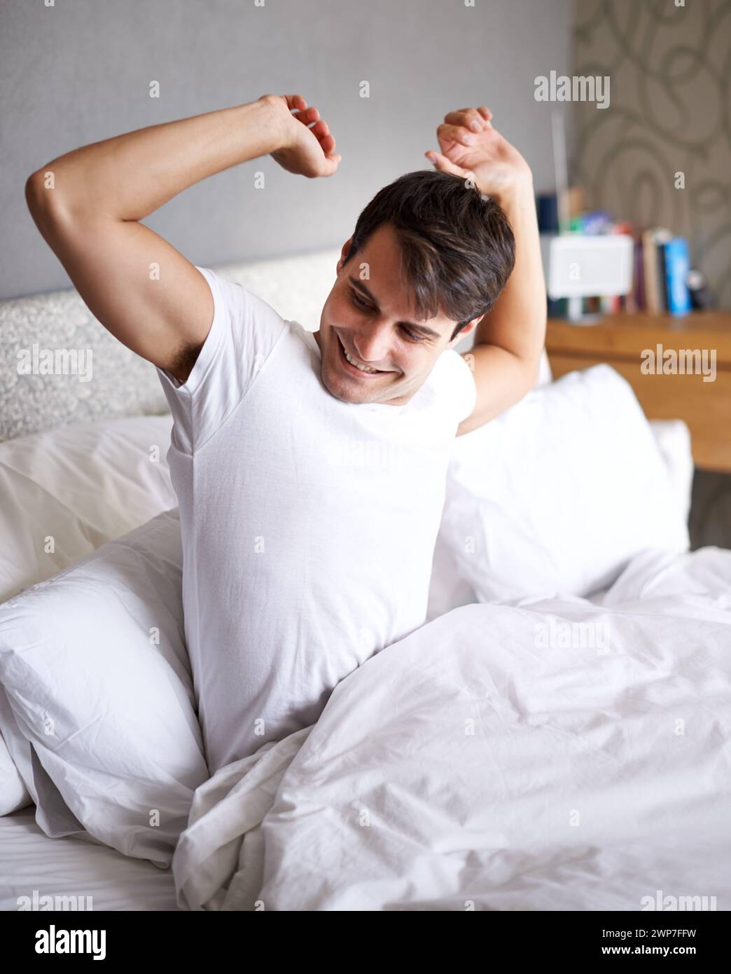 Man, morning and stretch in bed, awake and smile for daily routine and ...