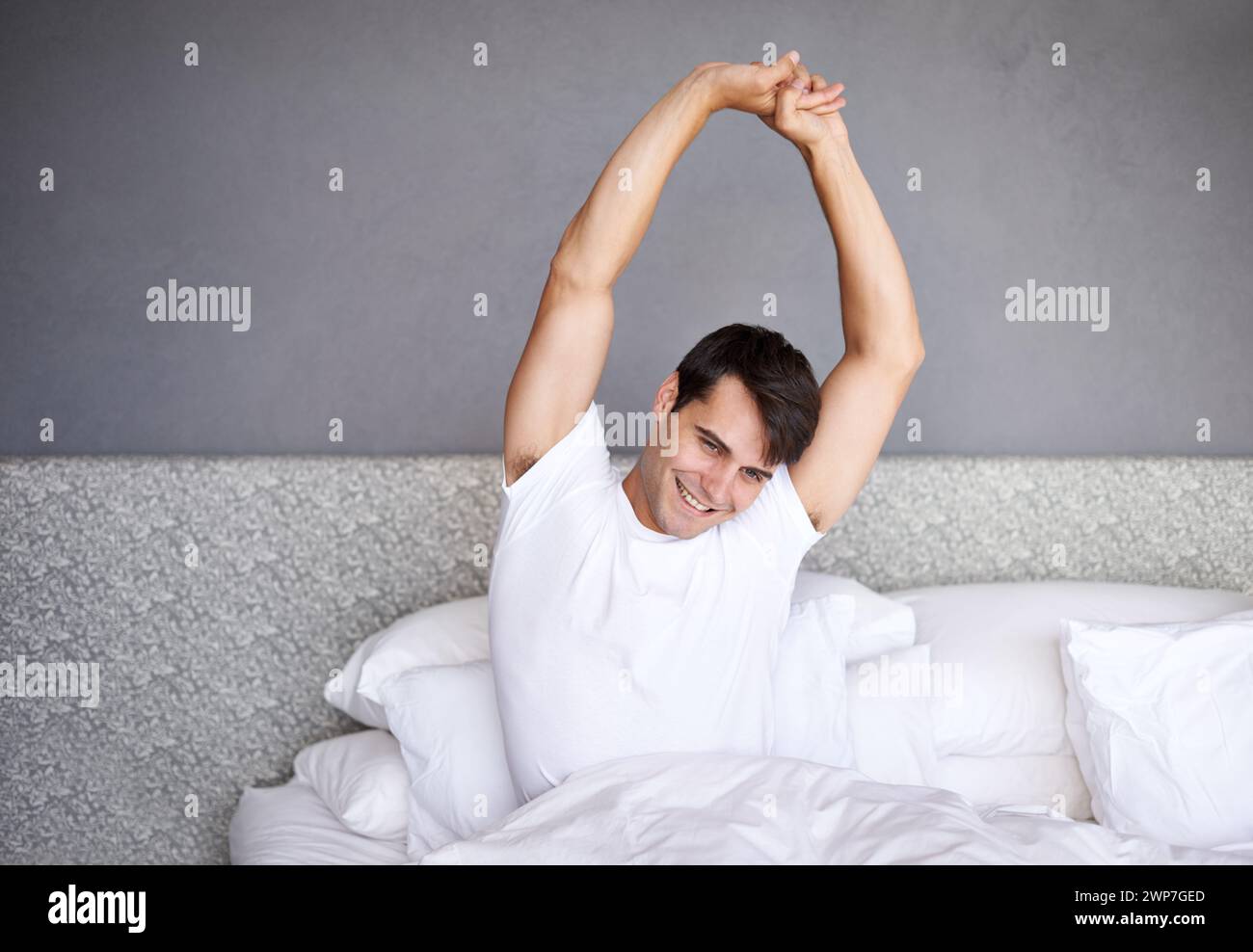 Man, morning and smile in bed, house and stretching for daily routine ...
