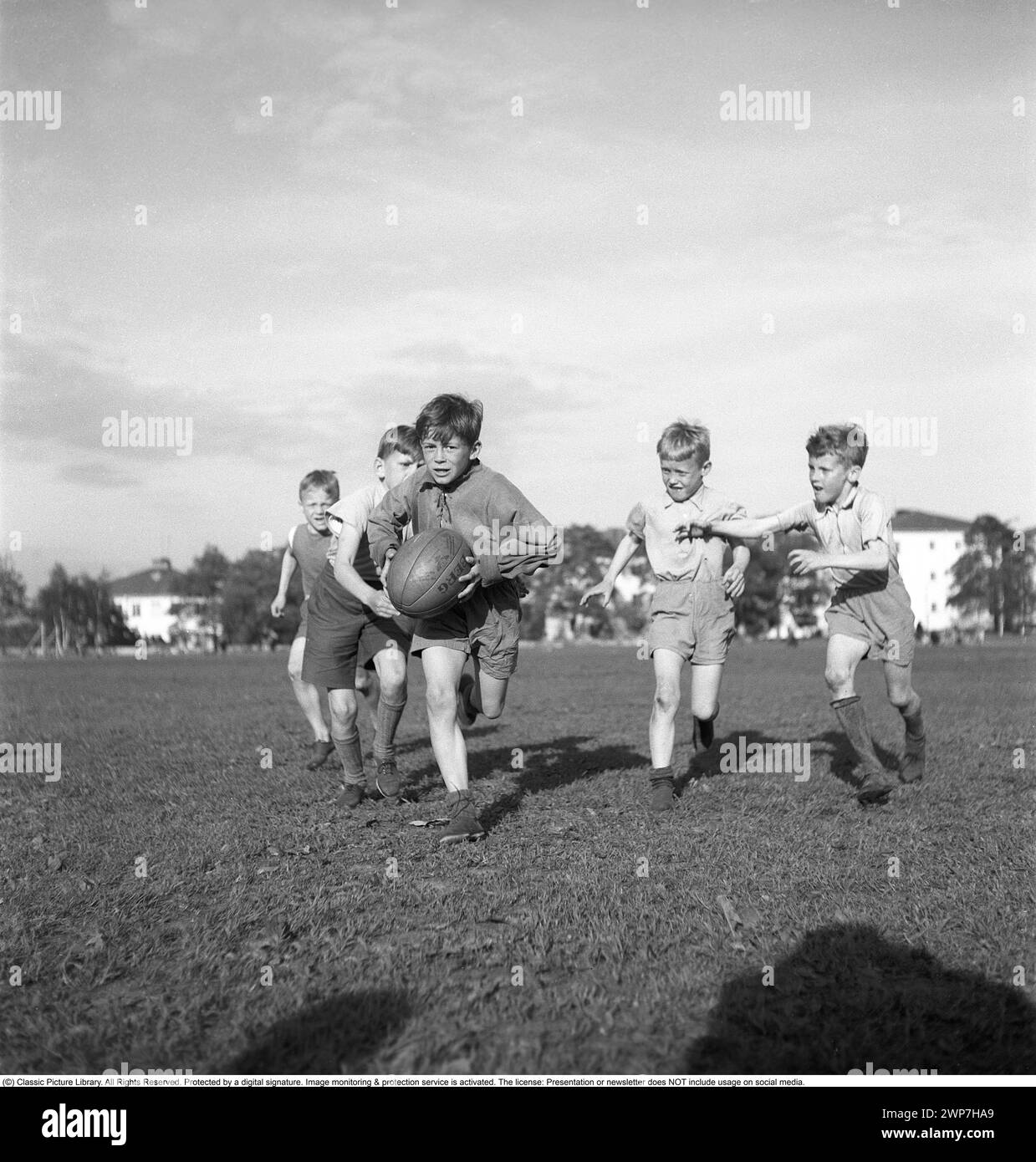 Rugby 1940. Young rugby players practise together. The boy running with ...