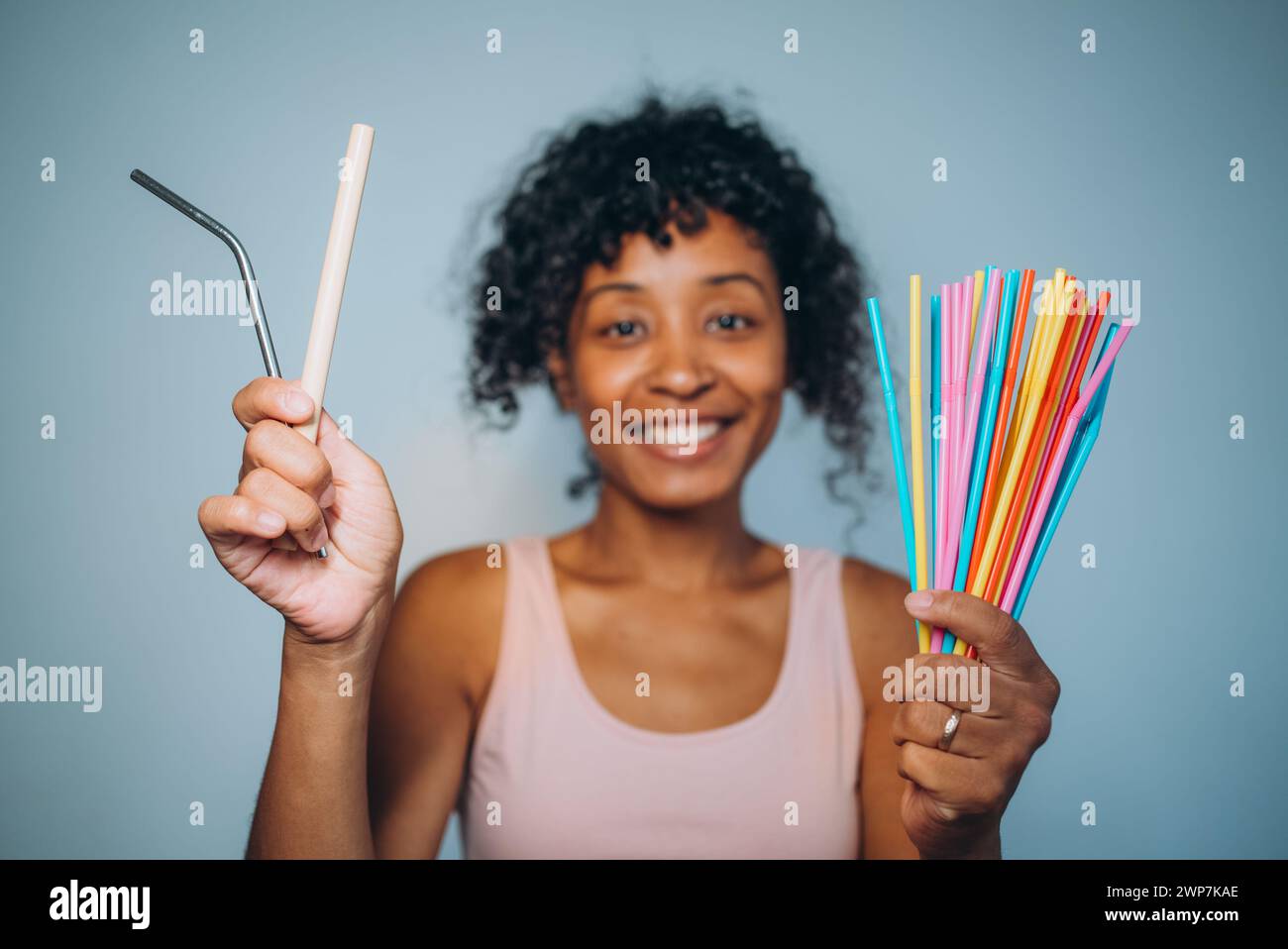 A cheerful woman presents a choice between a single reusable straw and ...