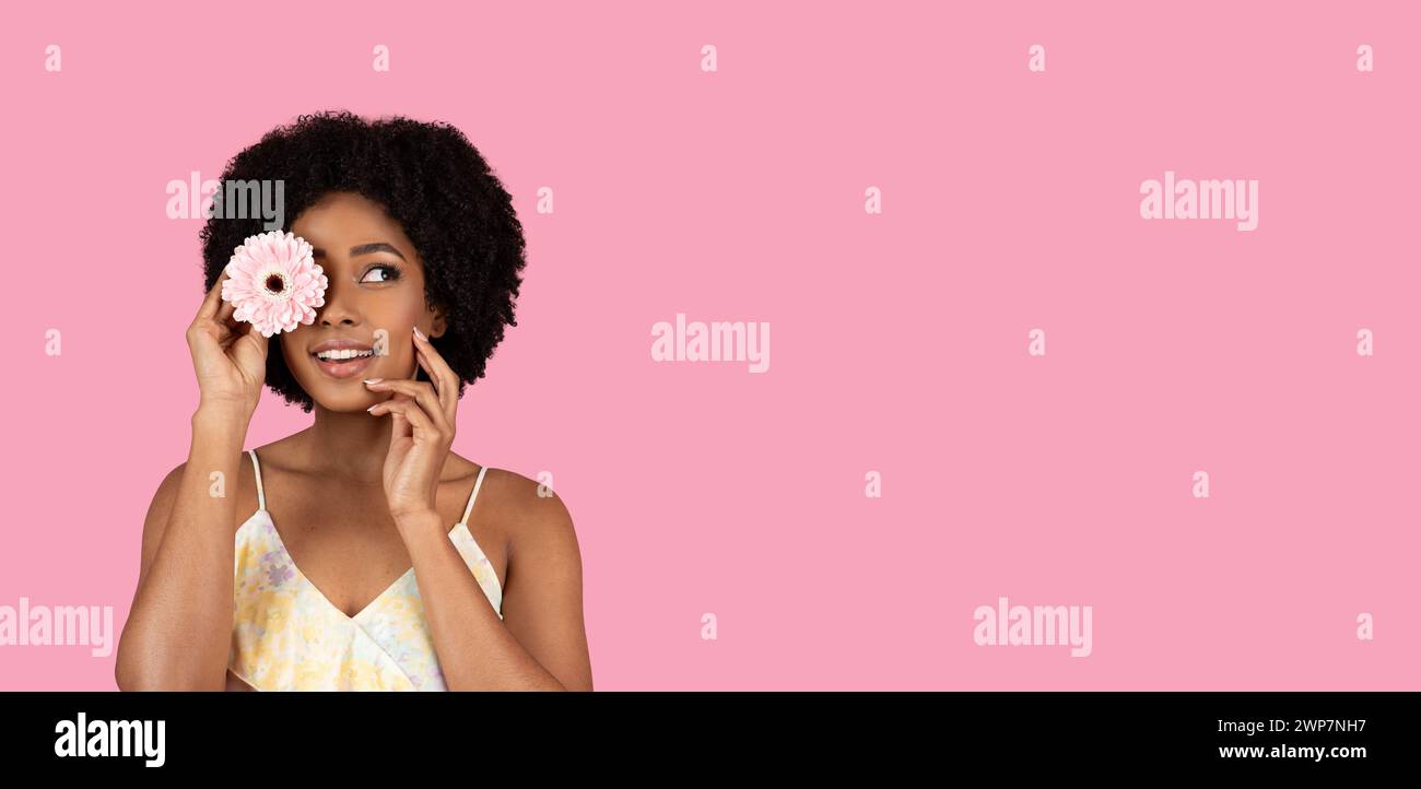 Playful African American woman with a natural hairstyle holding a pink ...