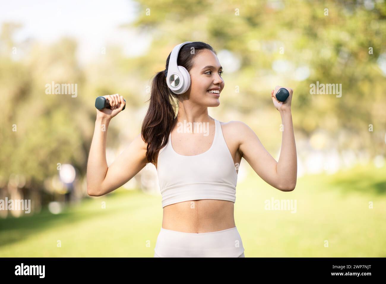 Radiant young woman wearing white workout clothes and headphones Stock ...