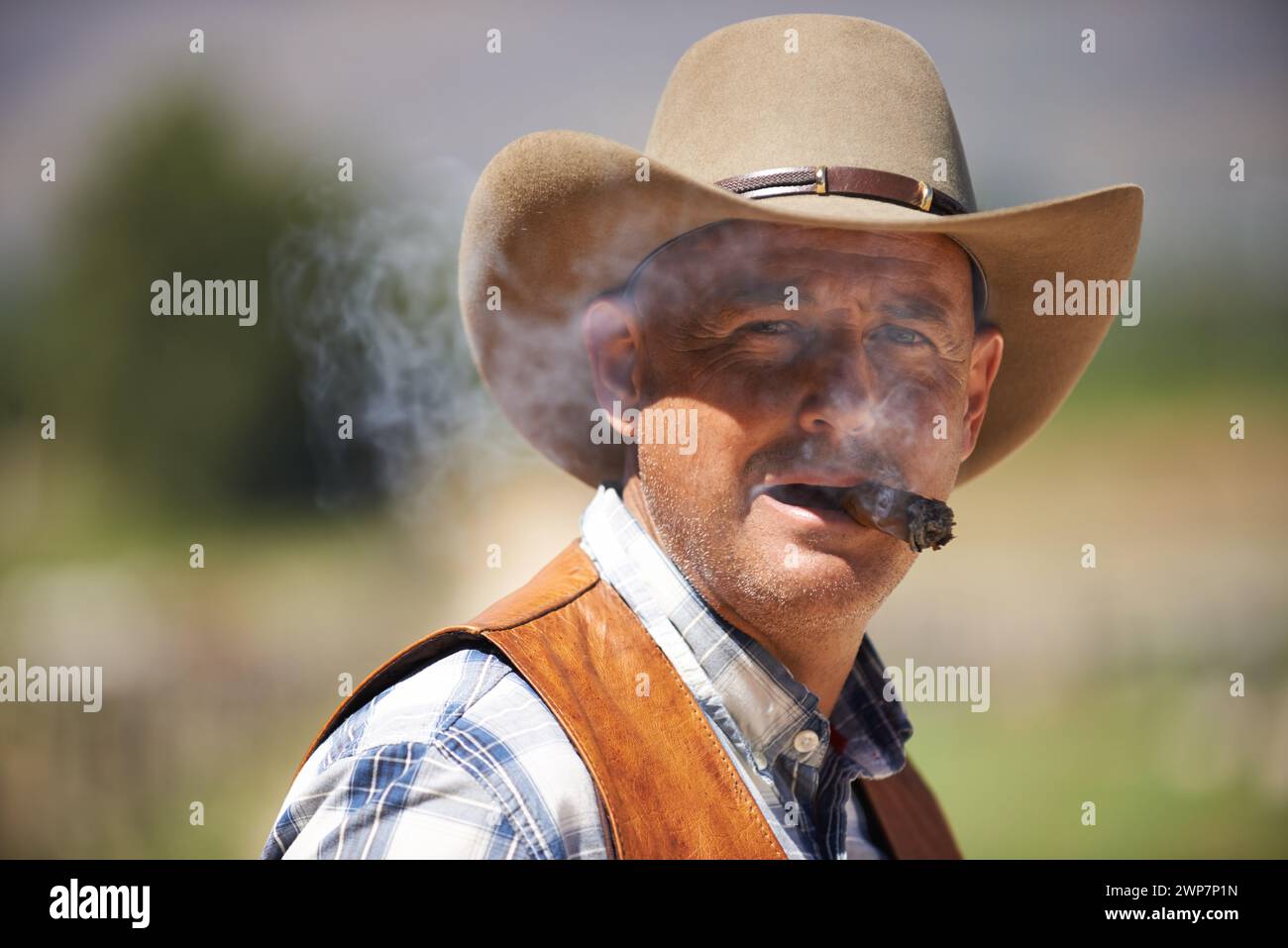 Portrait, cowboy and man smoking cigar at farm in the rural countryside ...