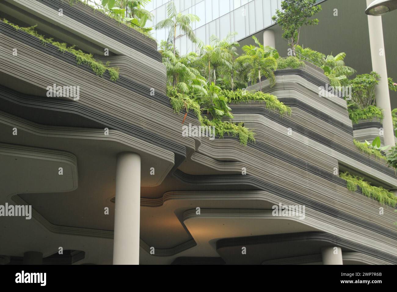 A multi-level building adorned with plants on its top and side in ...
