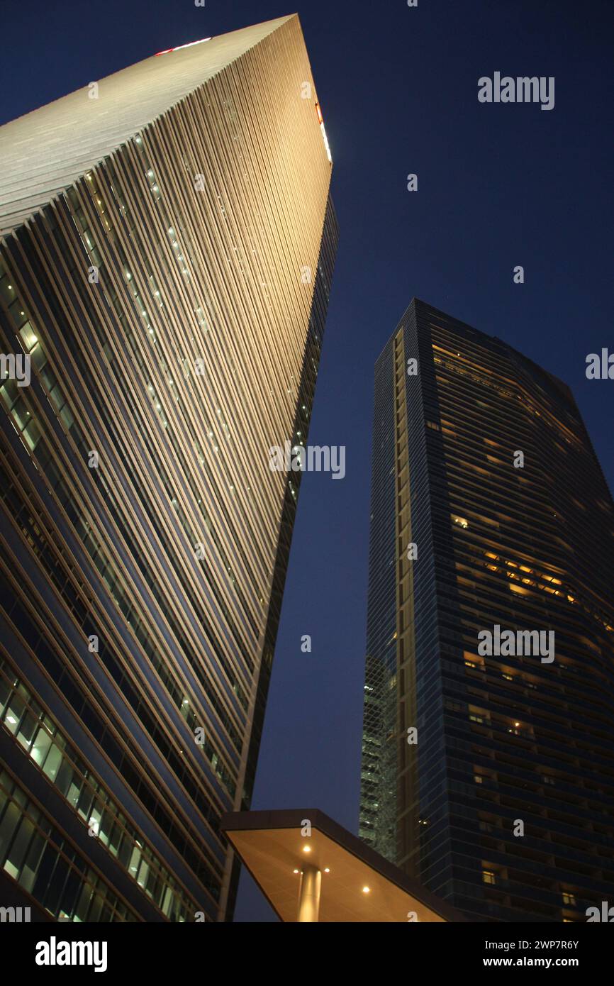 Two tall buildings with modern architecture in sunlight against a blue ...