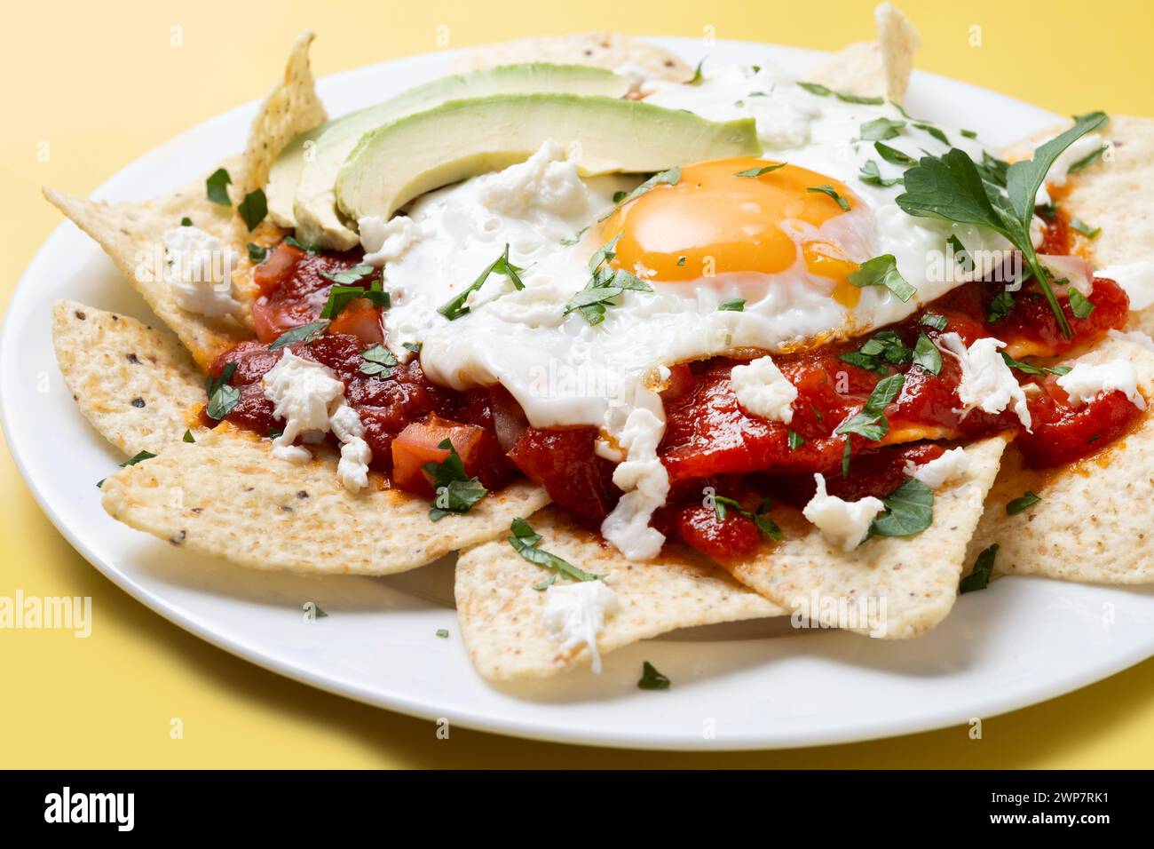 Traditional Mexican breakfast red chilaquiles with egg on yellow ...