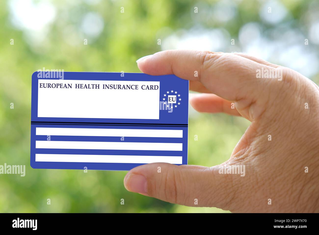 European health insurance card in hand on natural green background ...