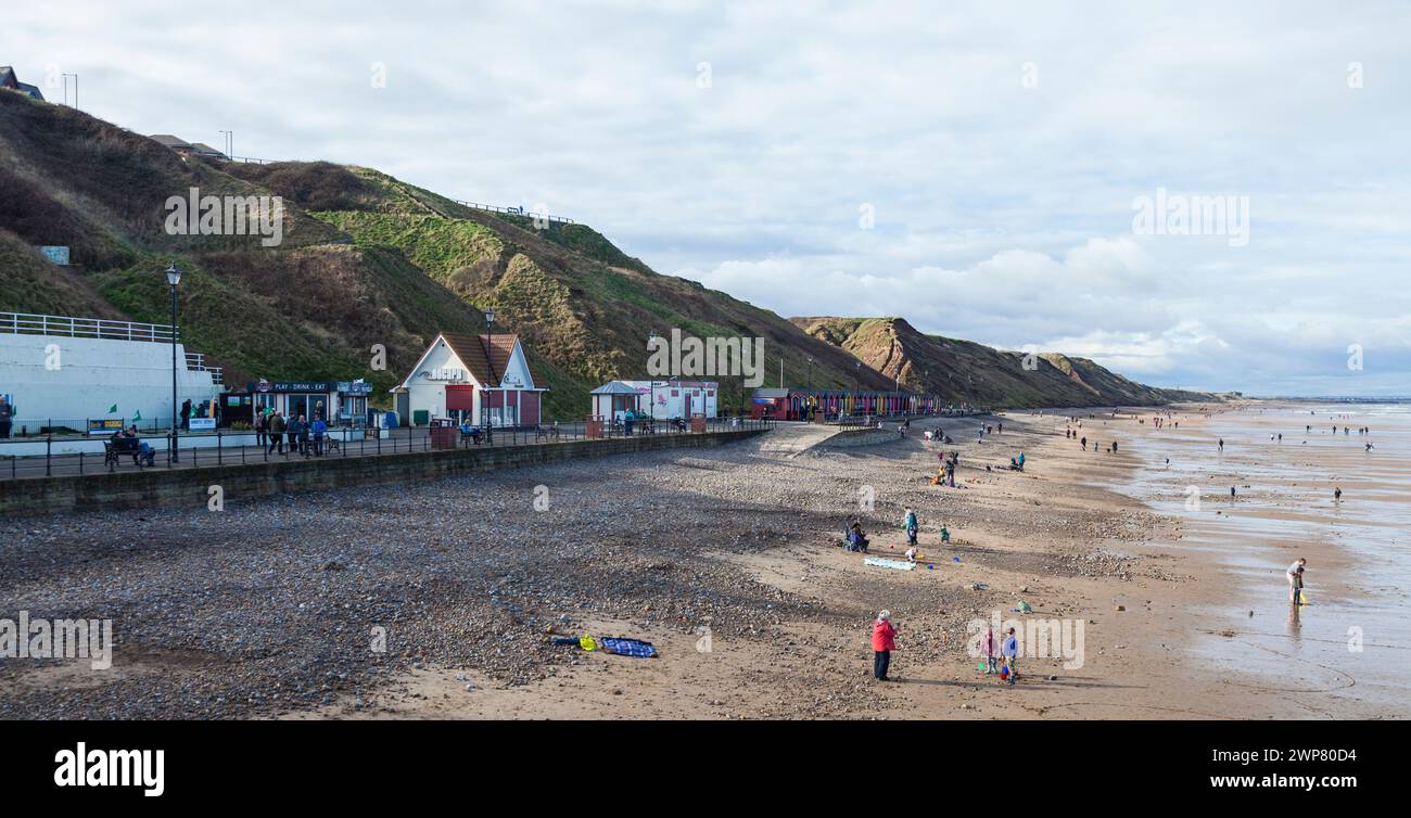 A view along the beach and the promenade with colourful beach huts at ...