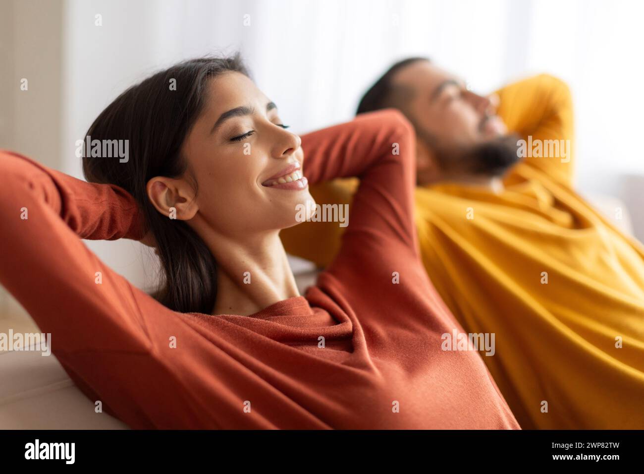 Relaxation Concept. Happy relaxed young couple leaning back on sofa at ...