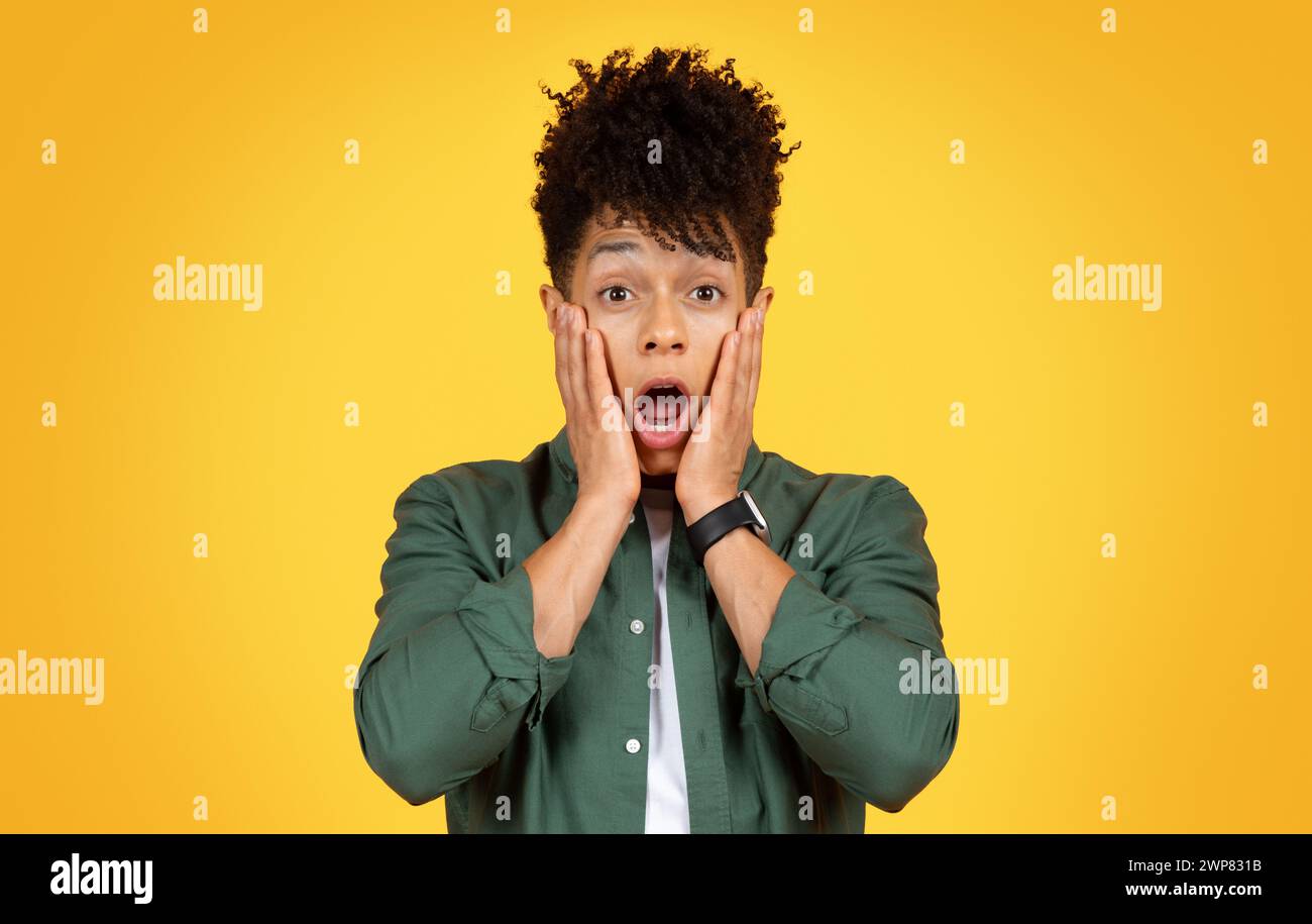 Shocked black guy grimacing and gesturing on yellow background Stock ...