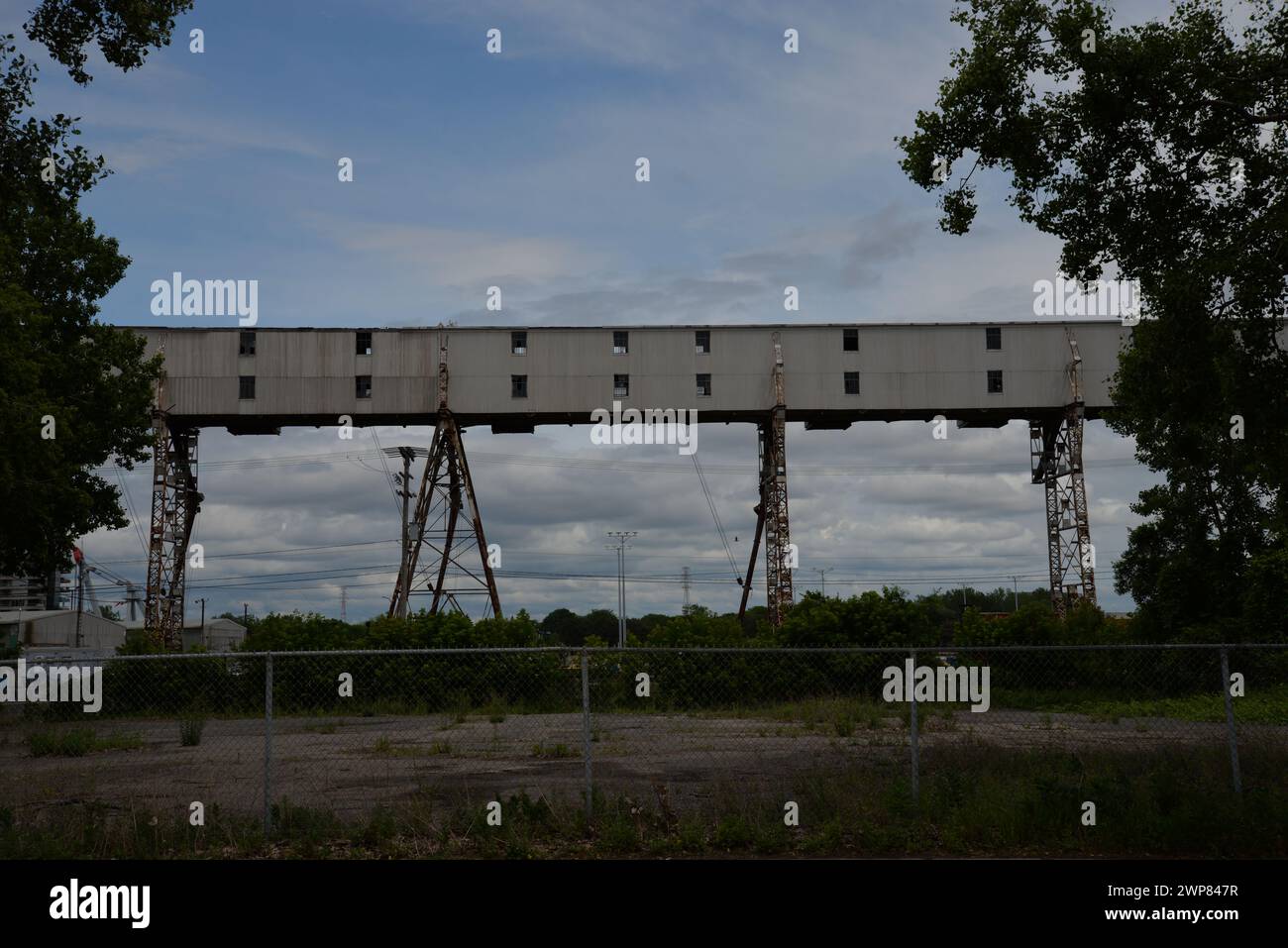 A vast bridge spans a verdant field under cloudy skies Stock Photo - Alamy