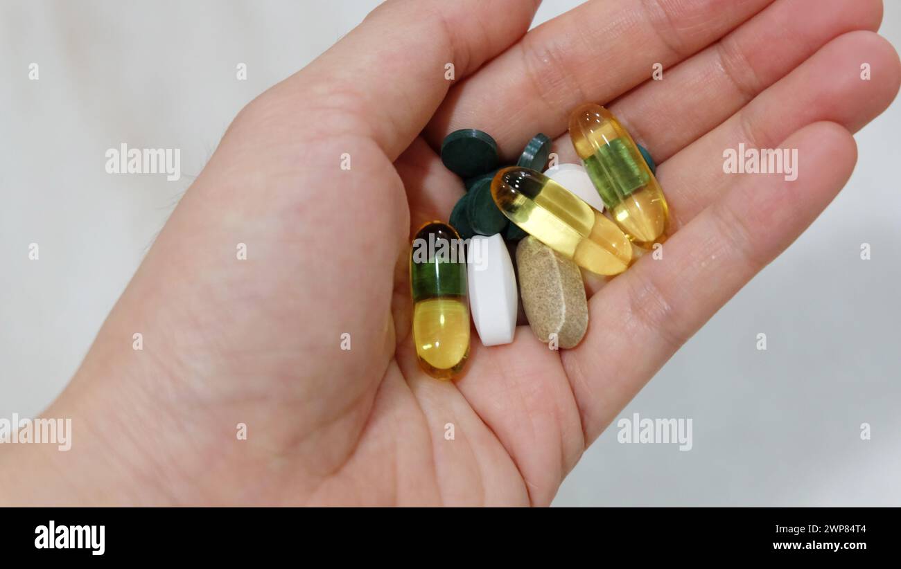 Closeup of hand holding assorted supplement pills and capsules Stock ...