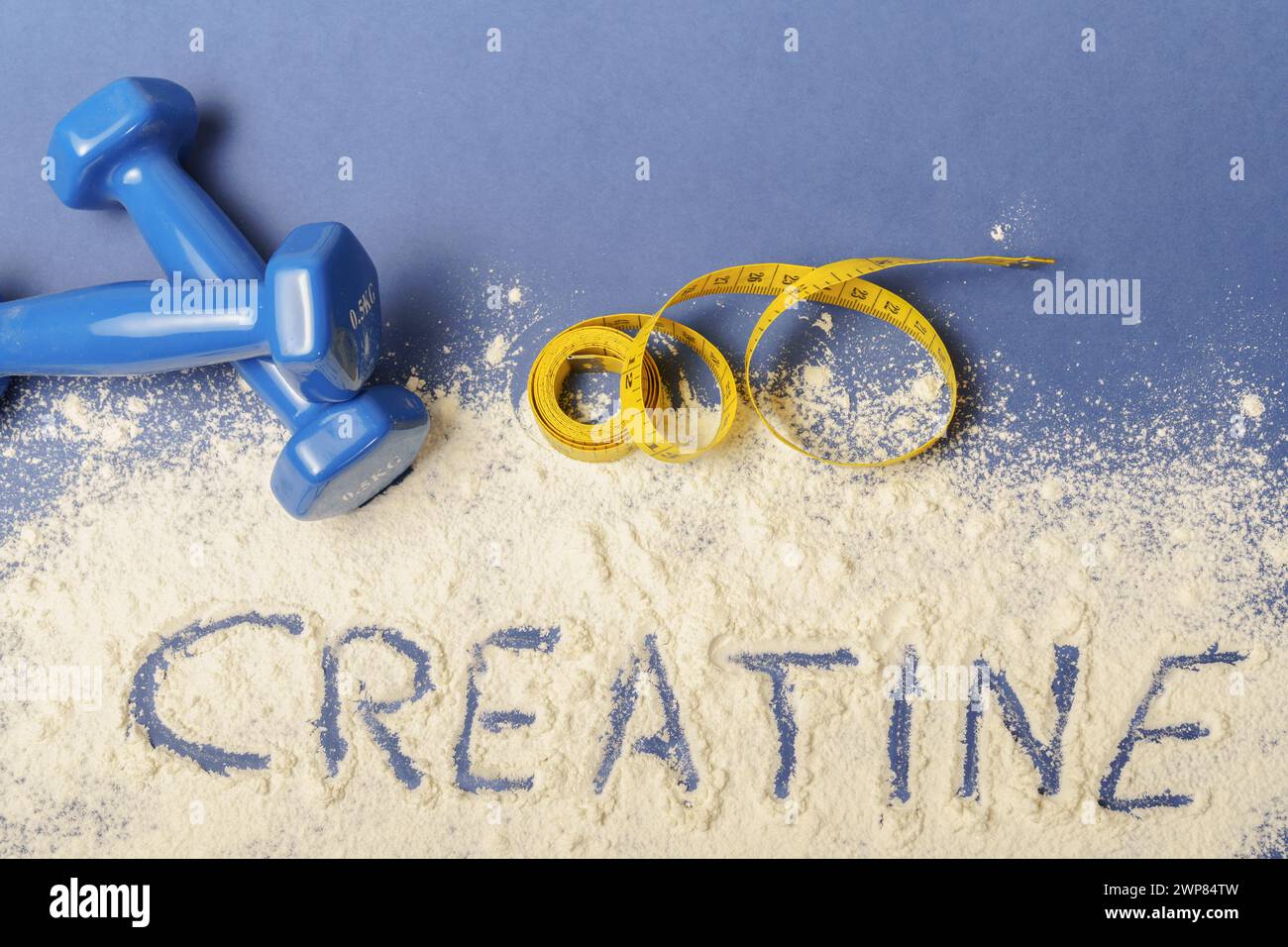 word creatine written on creatine powder on blue background, with ...