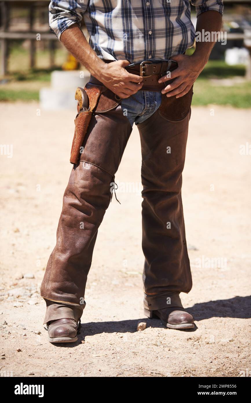 Farm, nature and legs of cowboy on ranch with weapon for horse, cows ...