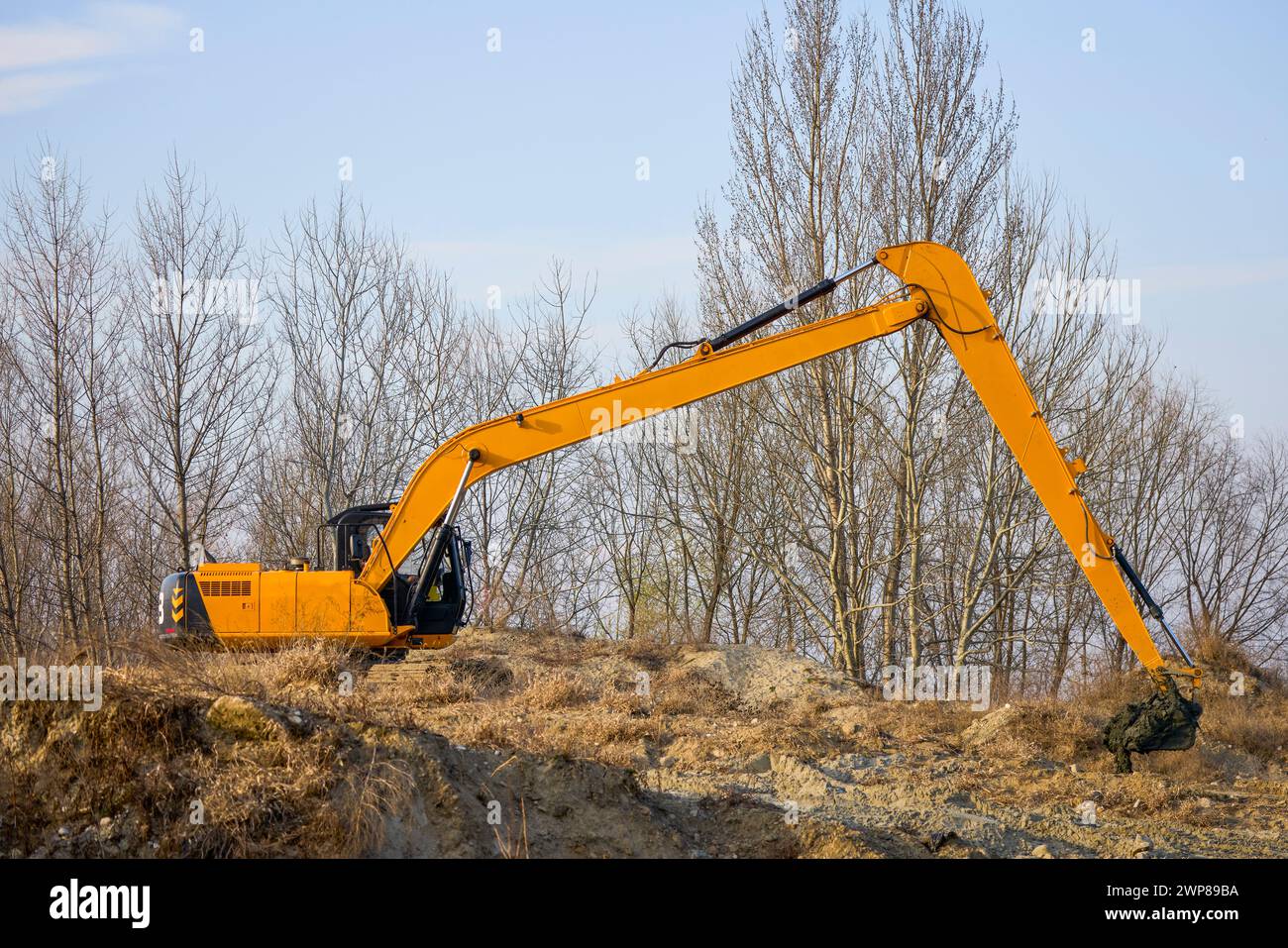 Earth digger, excavator, at the river's shore, working Stock Photo - Alamy