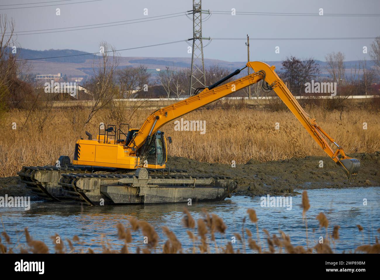 Earth digger, excavator, at the river's shore, working Stock Photo - Alamy