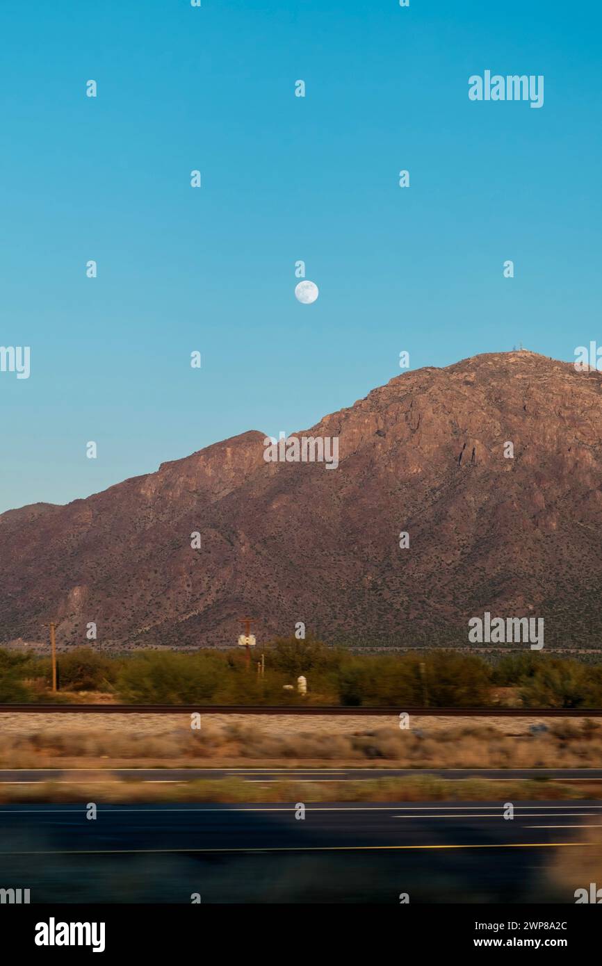 The Moon rising behind mountain peaks Stock Photo - Alamy
