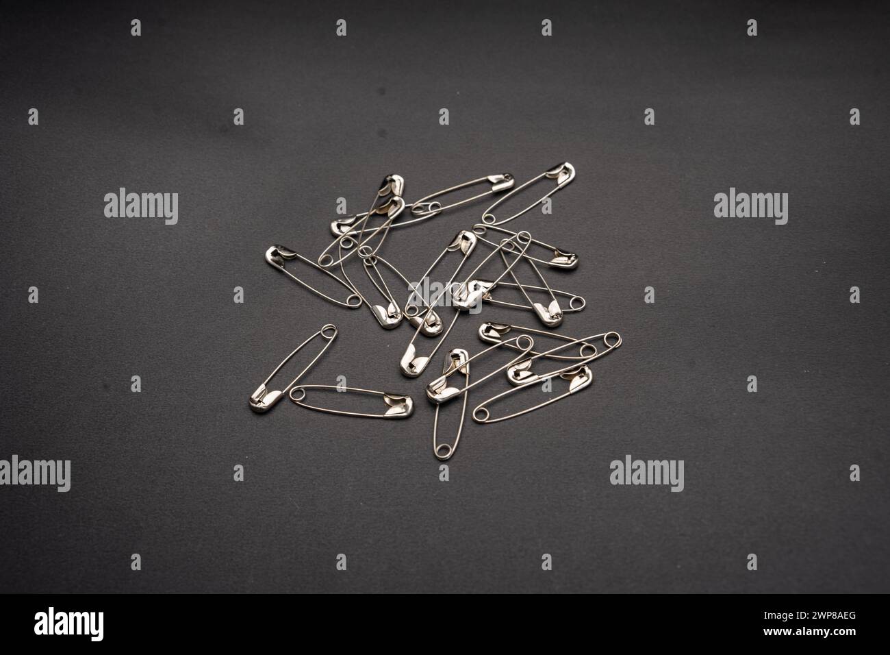 Close up a pile of scattered safety pins isolated on dark black ...