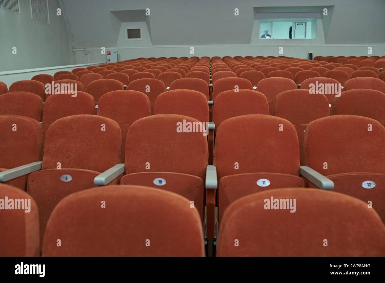 Empty cinema hall with orange seats with copy space. Seats with numbers ...