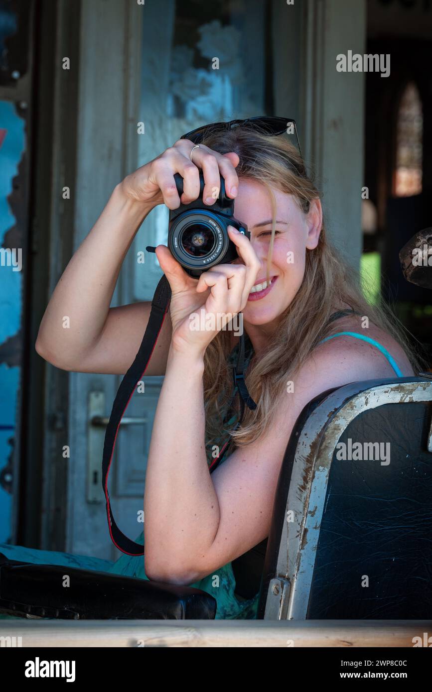 A blonde girl in a vintage chair aiming a camera at the viewer Stock ...