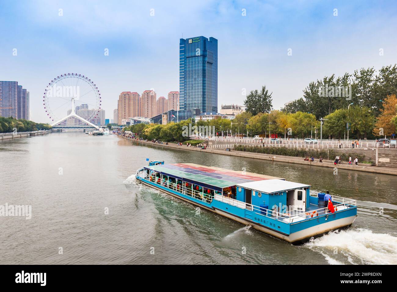 Tourist boat cruising towards the Tianjin Eye ferris wheel in Tianjin ...