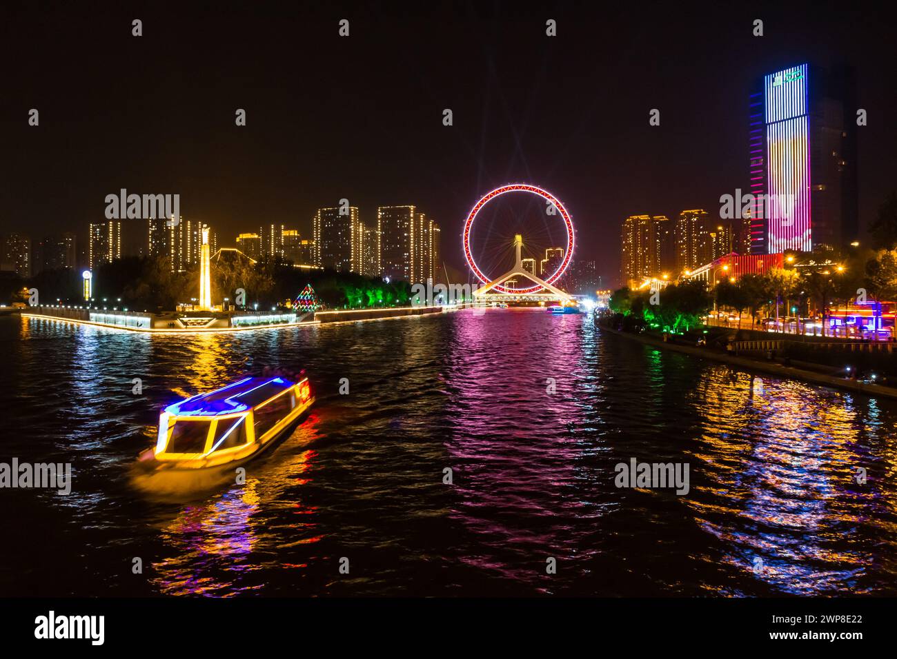 Night view over the illuminated tourist cruise boat and ferris wheel in ...