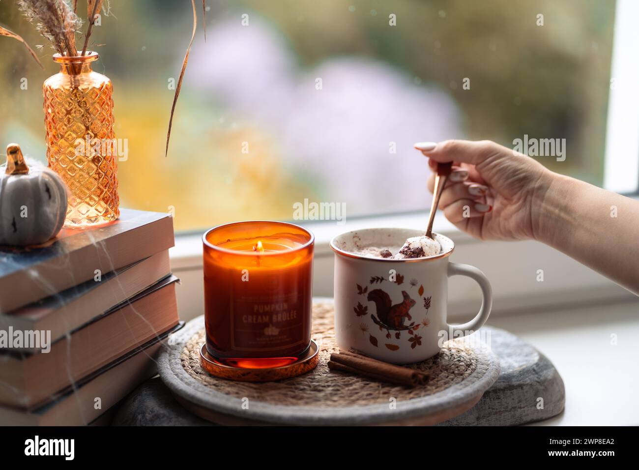 Candle on table with books and hot chocolate Stock Photo - Alamy